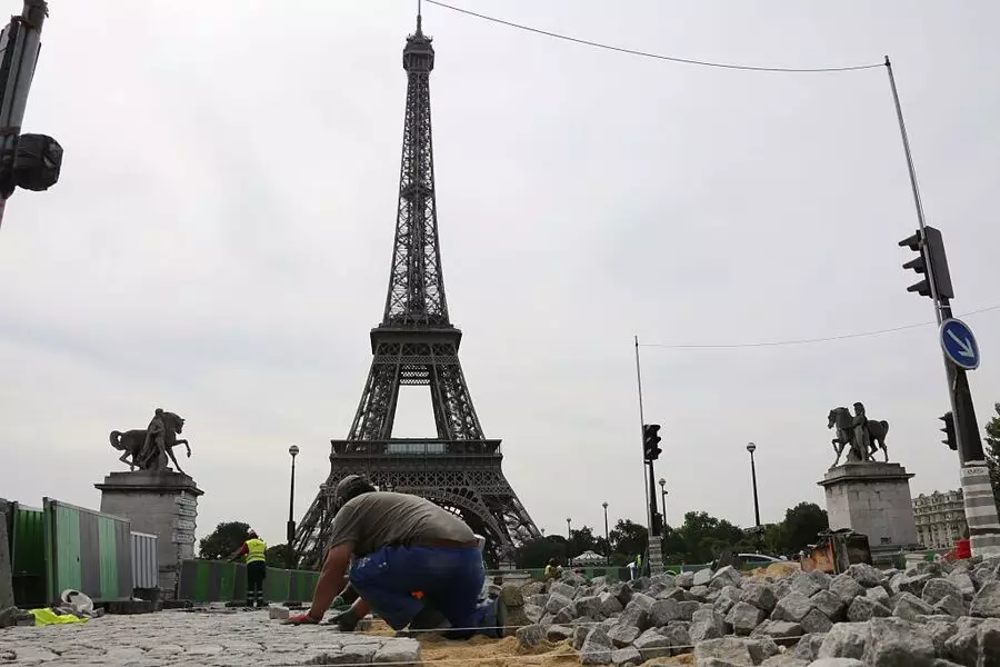 Dělník položí historickou dlážděnou dlažbu na silnici na Place de Varsovie u Eiffelovy věže v Paříži dne 26. června 2015. AFP PHOTO / LUDOVIC MARIN (Foto kredit by měl být LUDOVIC MARIN/AFP/Getty Images)